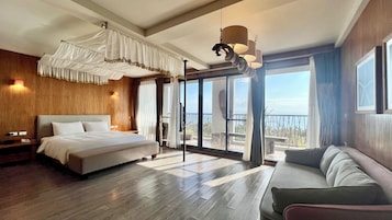 Quarto espaçoso com uma cama grande, um sofá e uma varanda com vista.