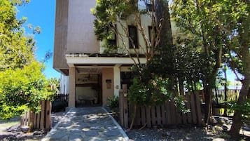 Um edifício com um caminho de pedra que leva à entrada, rodeado por árvores e uma cerca de madeira.