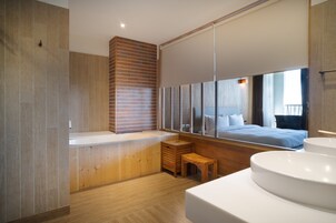 Uma casa de banho moderna com lavatório de madeira, um espelho grande e uma banheira.
