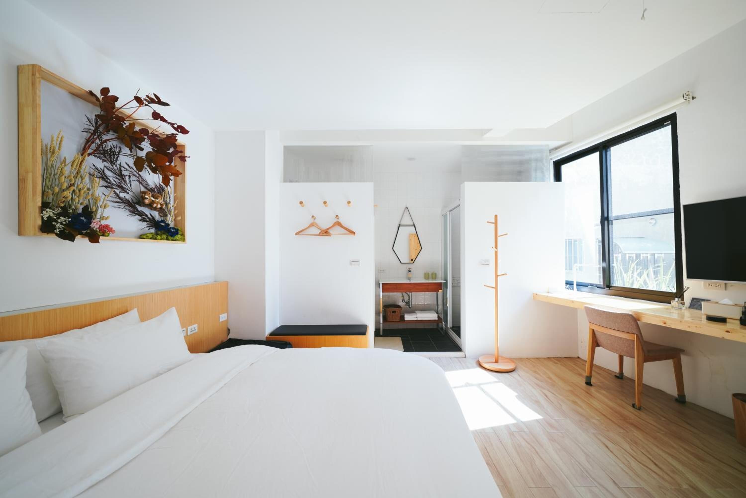 Quarto de hotel moderno com uma cama grande, uma mesa de escritório e vista para a cidade.