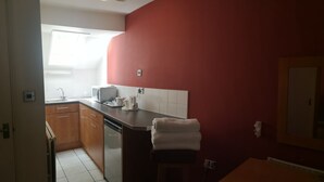 Cozinha compacta com micro-ondas, pia e armários de madeira.
