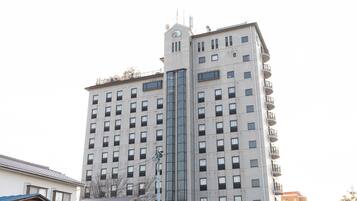 Um hotel moderno e alto, com vários andares, janelas amplas e uma antena proeminente no telhado.
