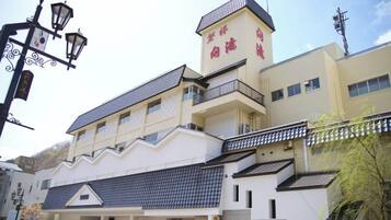 Um edifício de vários andares com telhado plano e uma pequena estrutura semelhante a uma torre no topo.