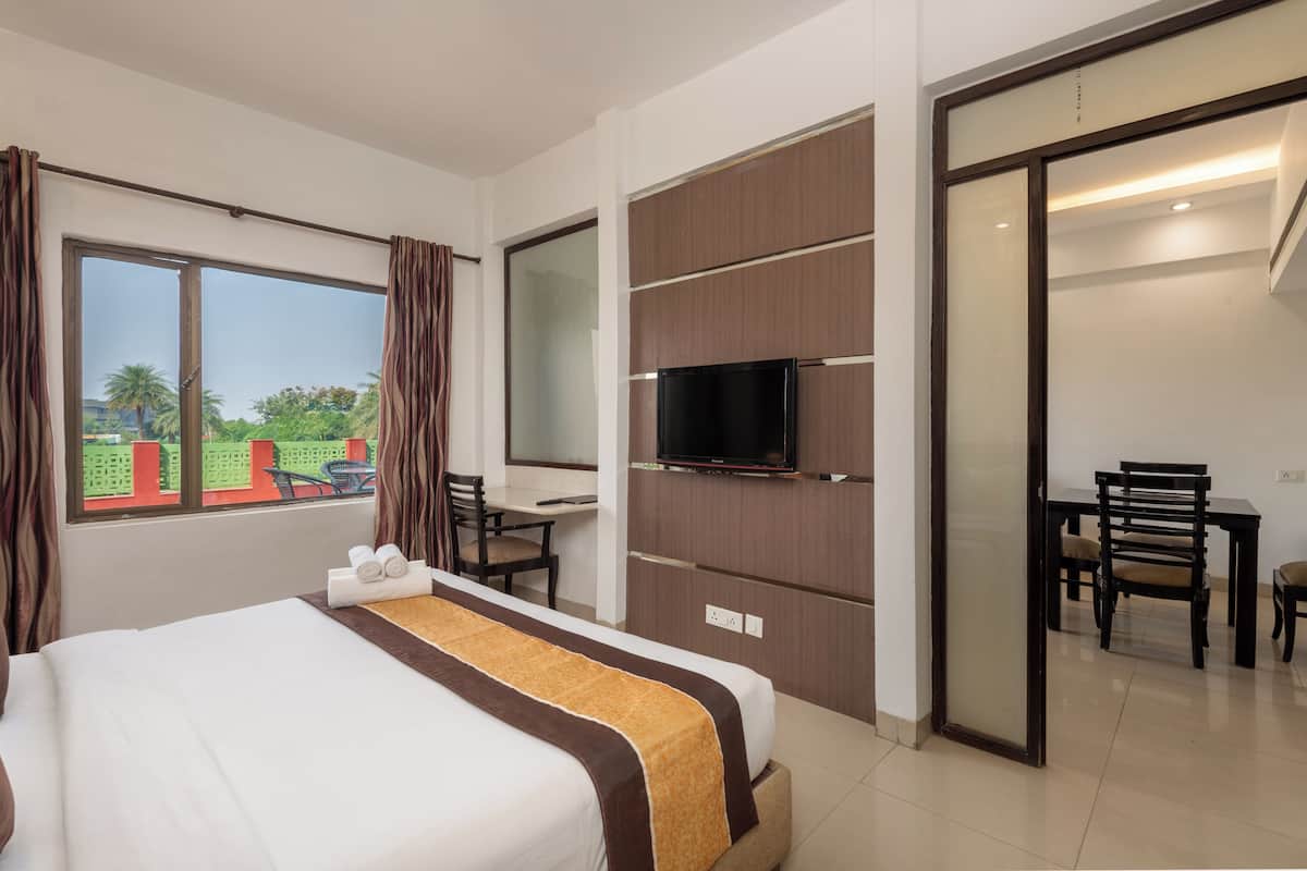 Quarto de hotel com cama, televisão na parede, secretária e cadeira.