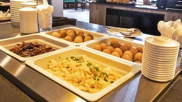 Buffet com diversas opções de comida, incluindo ovos, ovos mexidos e carne.