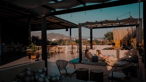 Uma área externa com mesas, cadeiras, piscina e vista para as montanhas.