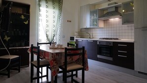 Uma cozinha moderna com área de refeições, com mesa e cadeiras, fogão, armários e uma televisão.