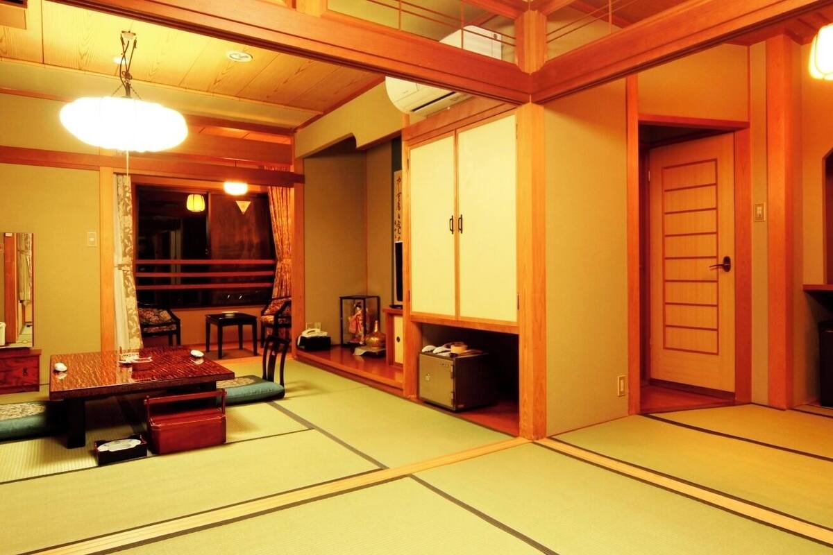 Um quarto japonês tradicional com tatames, uma mesa baixa e uma porta deslizante.