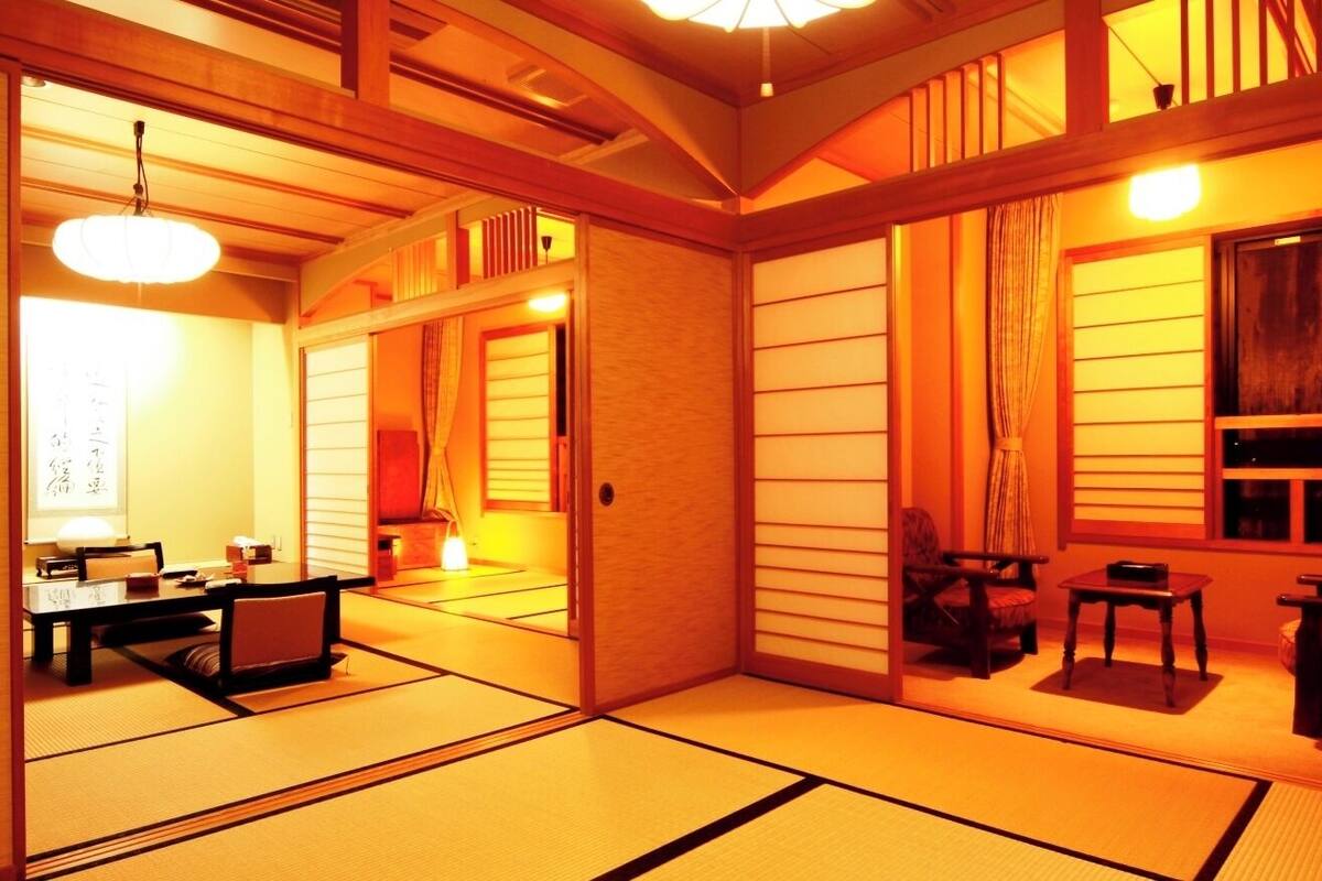 Um quarto japonês tradicional com tatames, portas deslizantes e uma mesa baixa com almofadas.