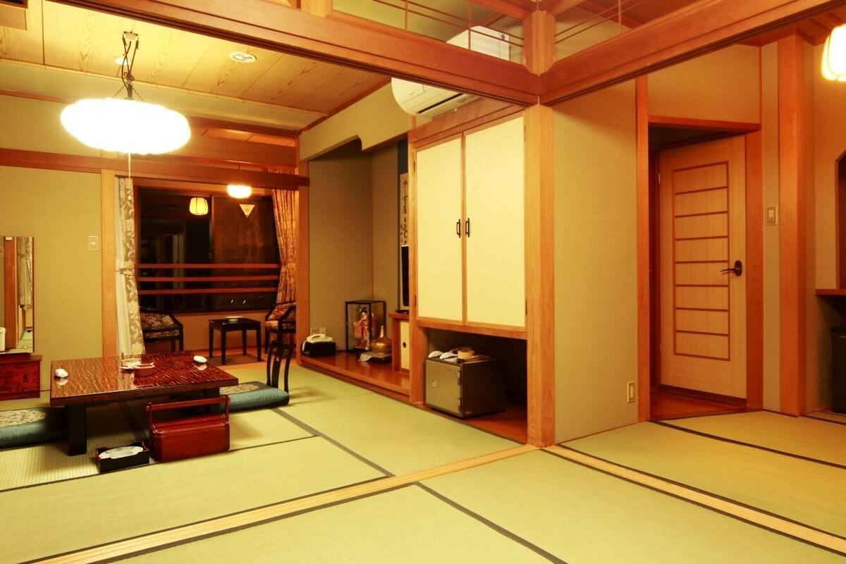 Um quarto japonês tradicional com tatames, uma mesa baixa com almofadas, um armário e uma porta deslizante.