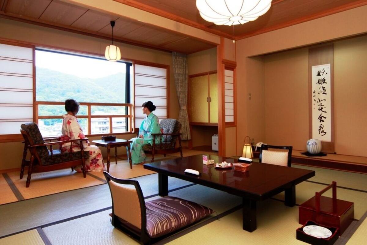 Um quarto japonês tradicional com tatames, uma mesa baixa e uma televisão.