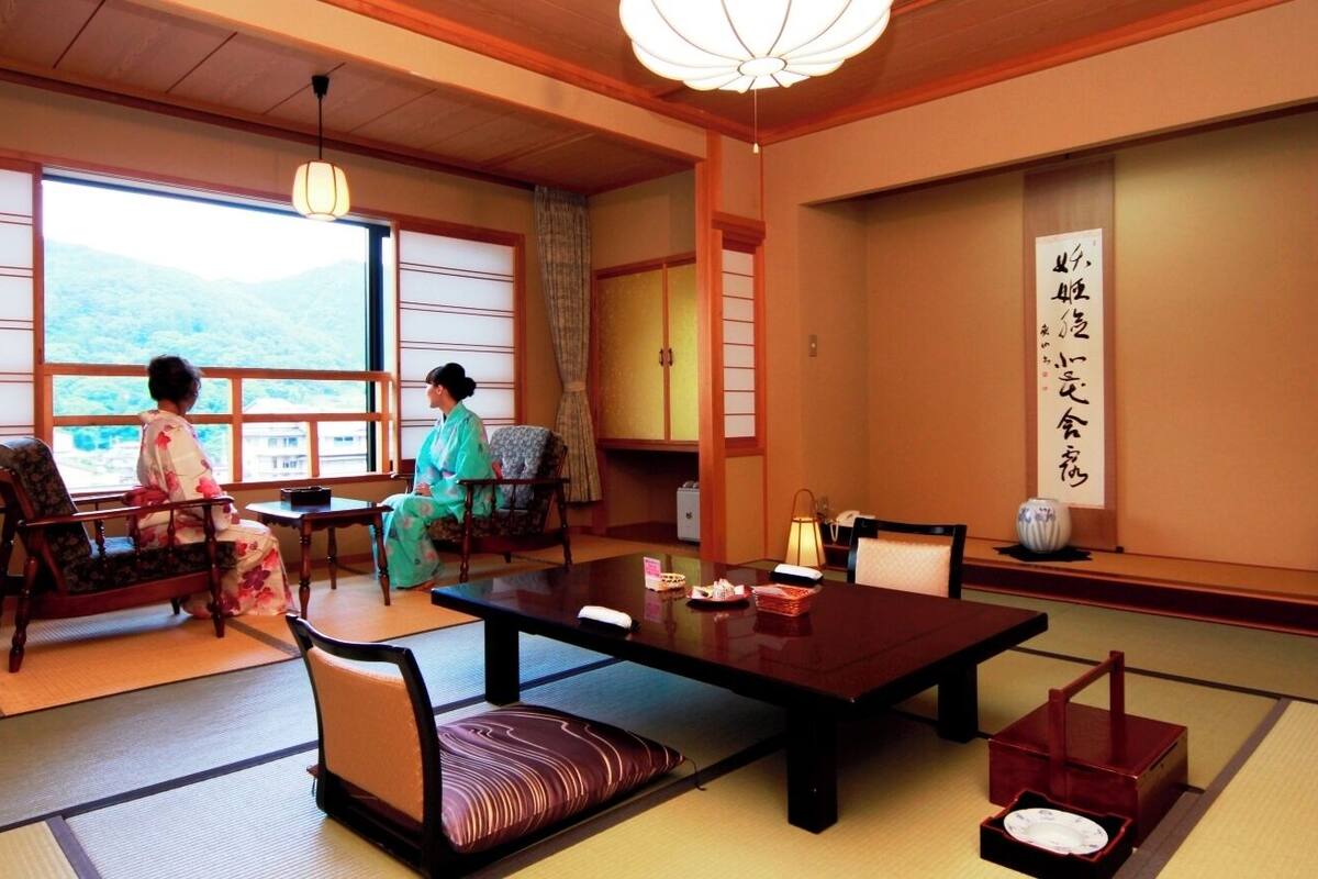 Um quarto japonês tradicional com tatames, uma mesa baixa e um sofá.