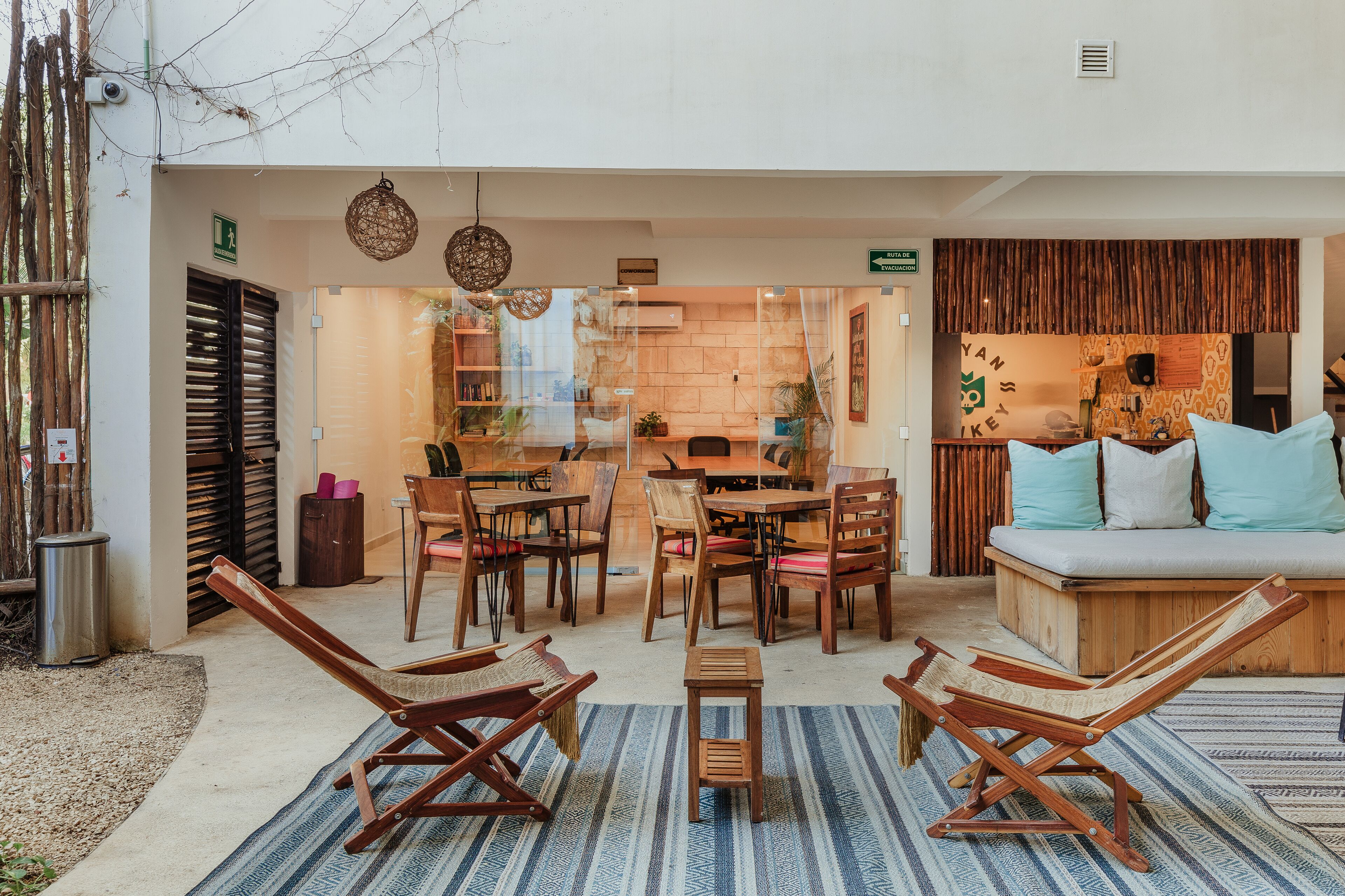 Interior acolhedor com mobiliário de madeira, um espaço para sentar e uma cozinha visível através de uma divisória de vidro.