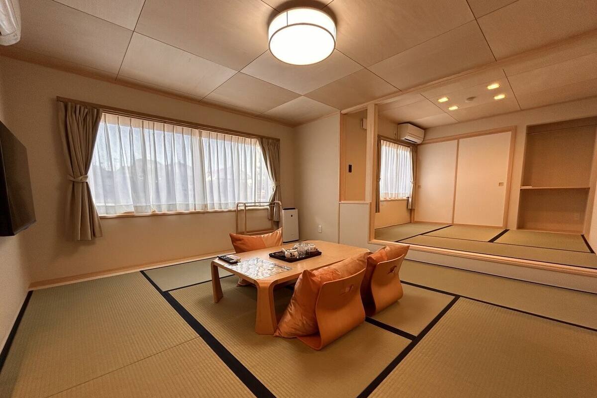 Um quarto japonês tradicional com tatames, uma mesa baixa com almofadas e portas deslizantes.