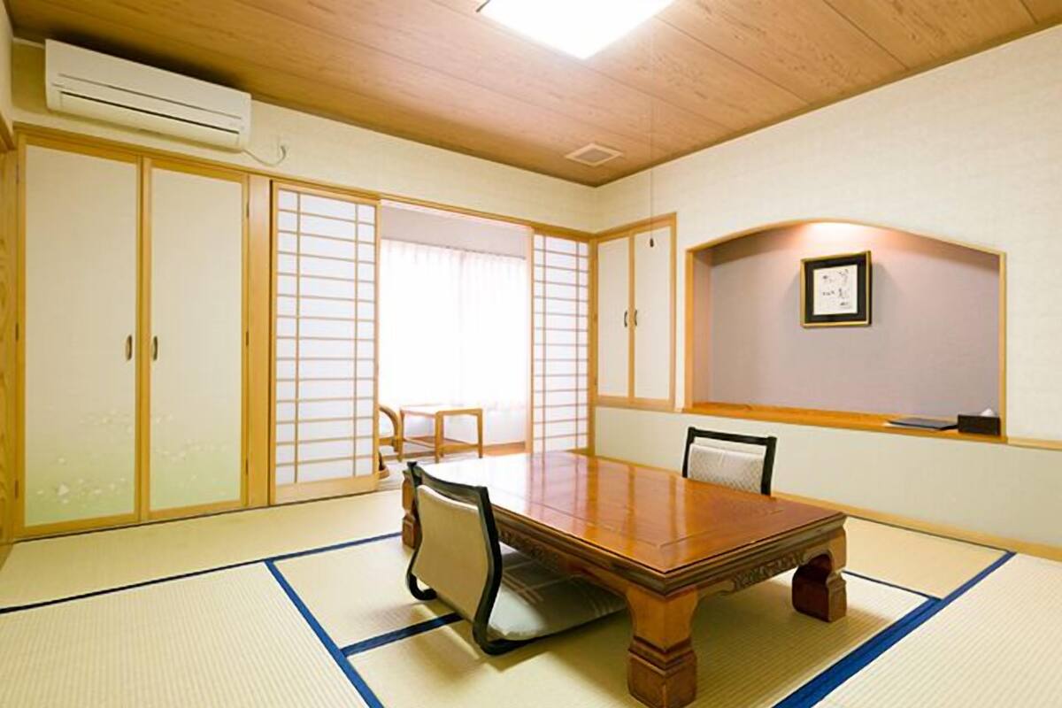 Um quarto japonês tradicional com tatames, uma mesa de madeira e portas deslizantes.