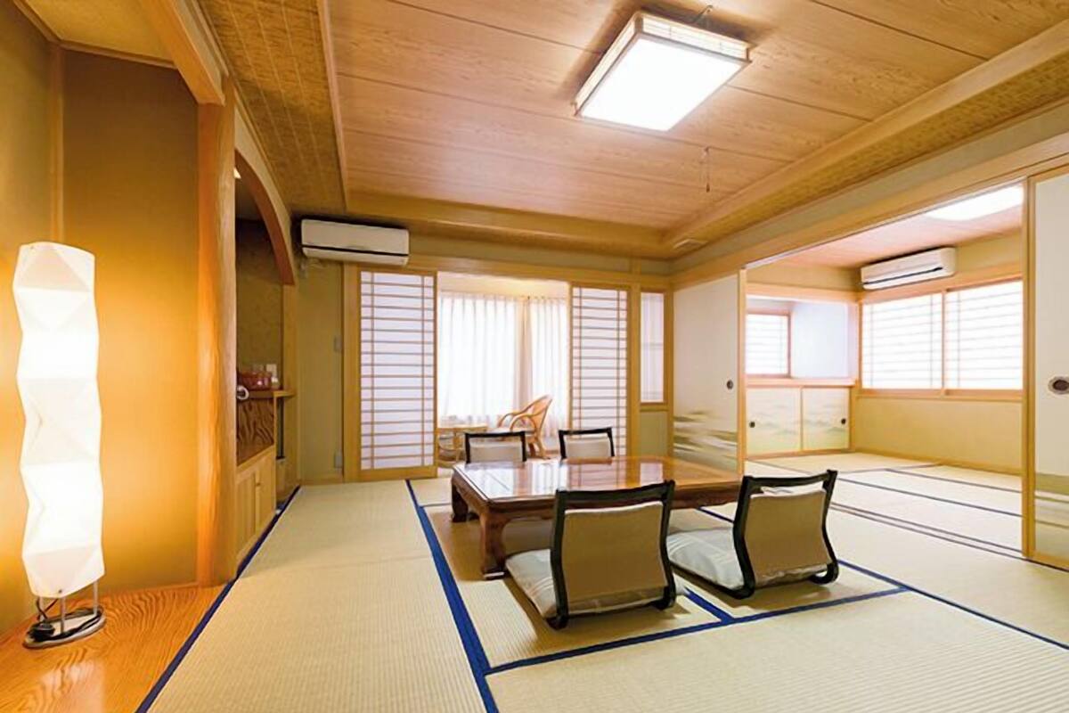 Um quarto japonês tradicional com tatames, uma mesa baixa com almofadas e portas deslizantes.