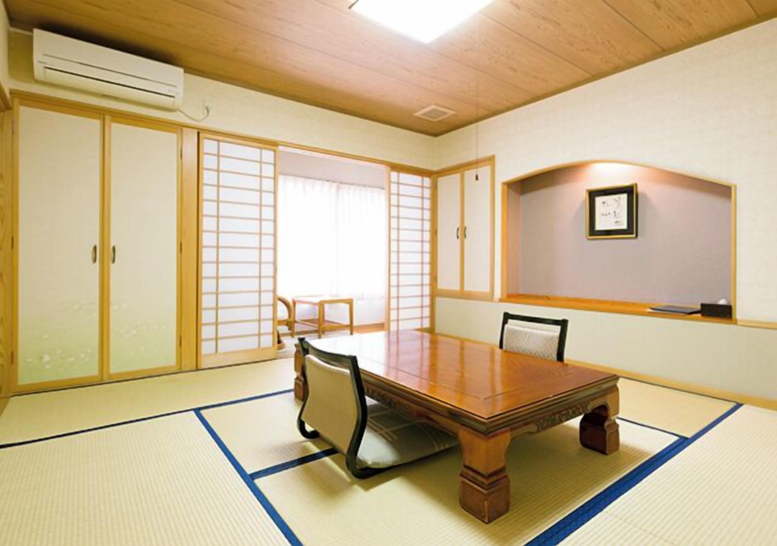 Um quarto japonês tradicional com piso de tatame, uma mesa baixa e portas deslizantes.