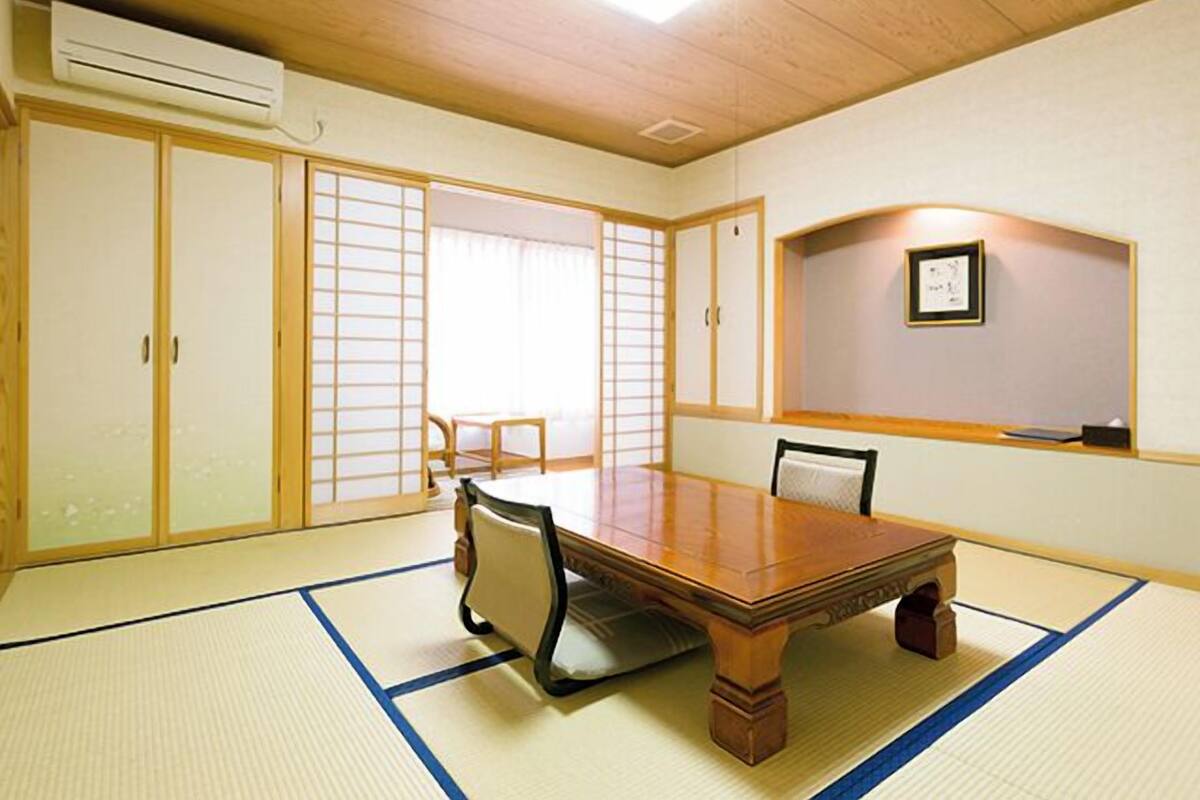 Um quarto japonês tradicional com piso de tatame, uma mesa baixa e portas deslizantes.