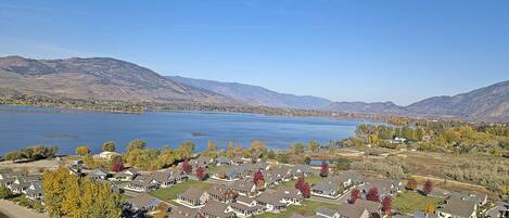 Zona residencial com casas perto de um lago, rodeada por montanhas.