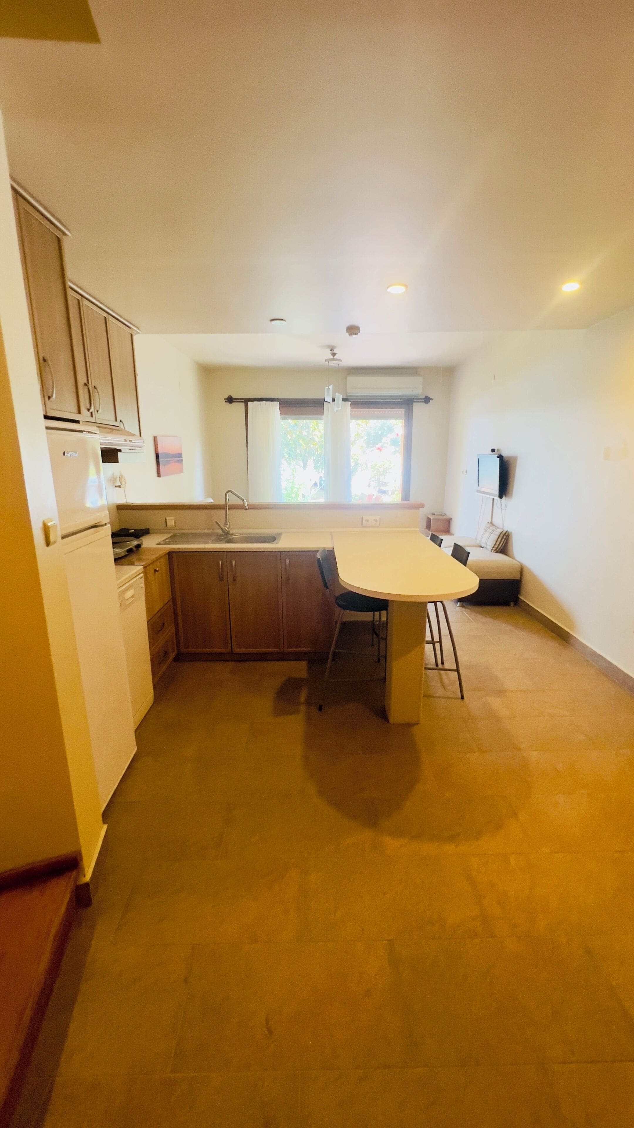 Uma cozinha compacta com área de refeições, forno embutido e janela com cortinas.