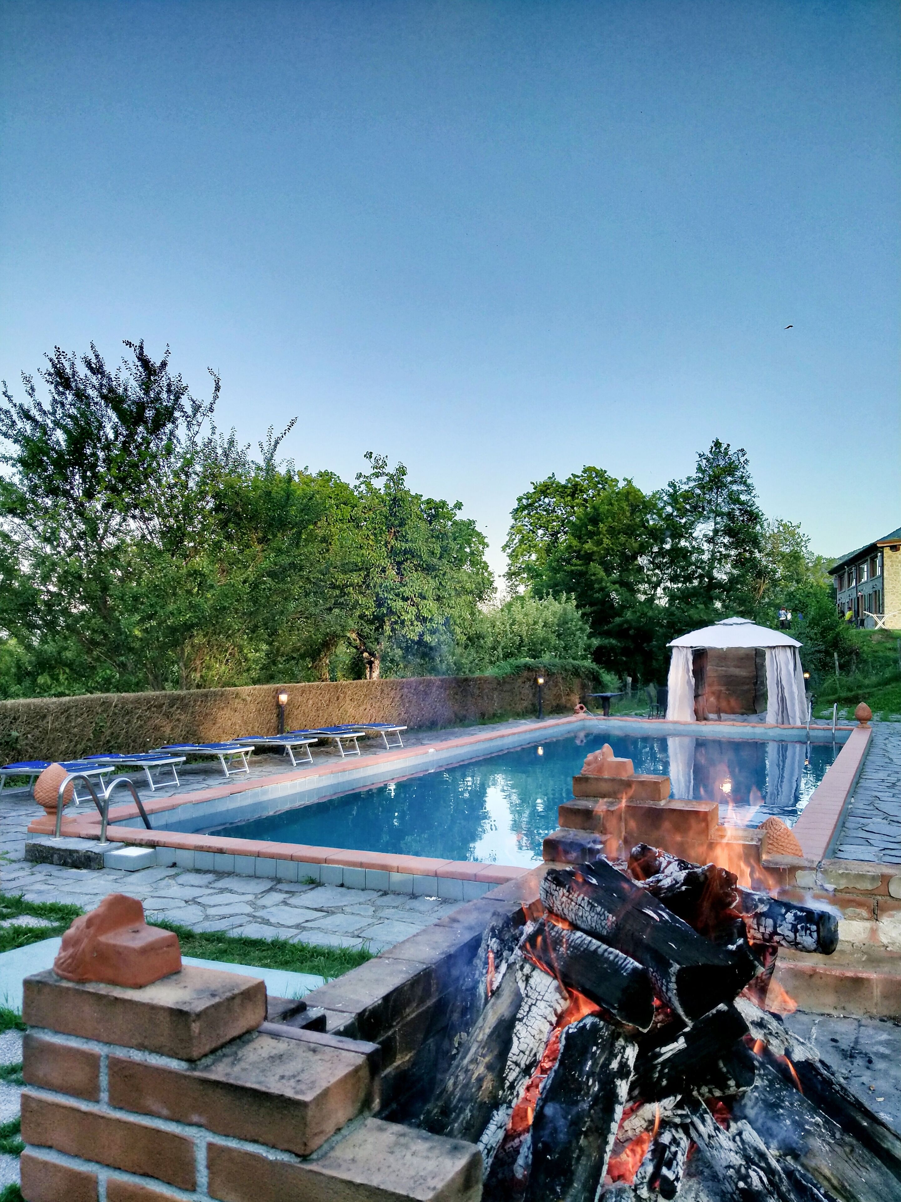 Piscina com lareira, cadeiras de descanso e área de estar coberta.