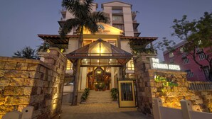 Entrada de hotel com fachada de pedra, área de acesso coberta e placa com a inscrição "The Guwahati Address".