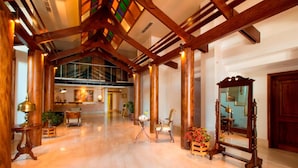 Um hall amplo com pé direito alto, vigas de madeira e piso lustroso.