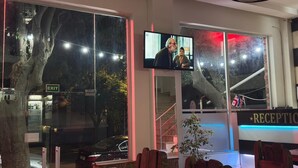 Uma área de recepção com televisão, escada e balcão.