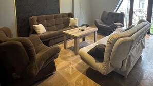 Uma sala de estar com um sofá marrom, uma poltrona cinza e uma mesa de centro de madeira.