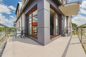 Um edifício moderno com grandes janelas, uma varanda com área de estar ao ar livre e vista ampla do céu.
