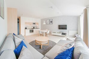 Uma sala de estar moderna com sofá, mesa de jantar e área de cozinha.
