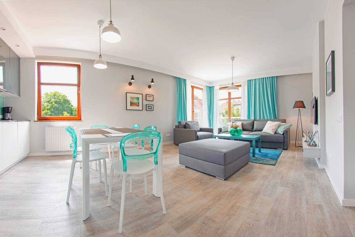 Uma sala de estar ampla com uma mesa de jantar, cadeiras, um sofá e uma mesa de centro.