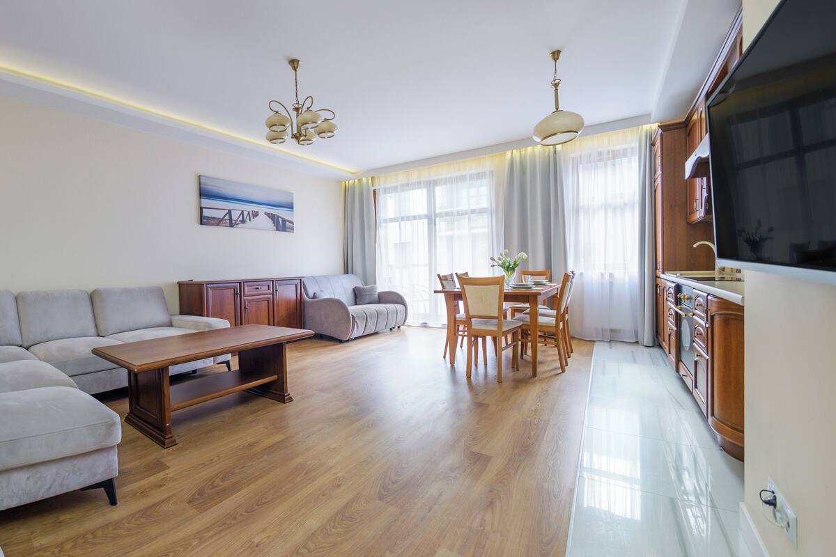 Uma sala de estar moderna com um sofá, uma mesa de centro de madeira e uma área de jantar com cadeiras e uma mesa.