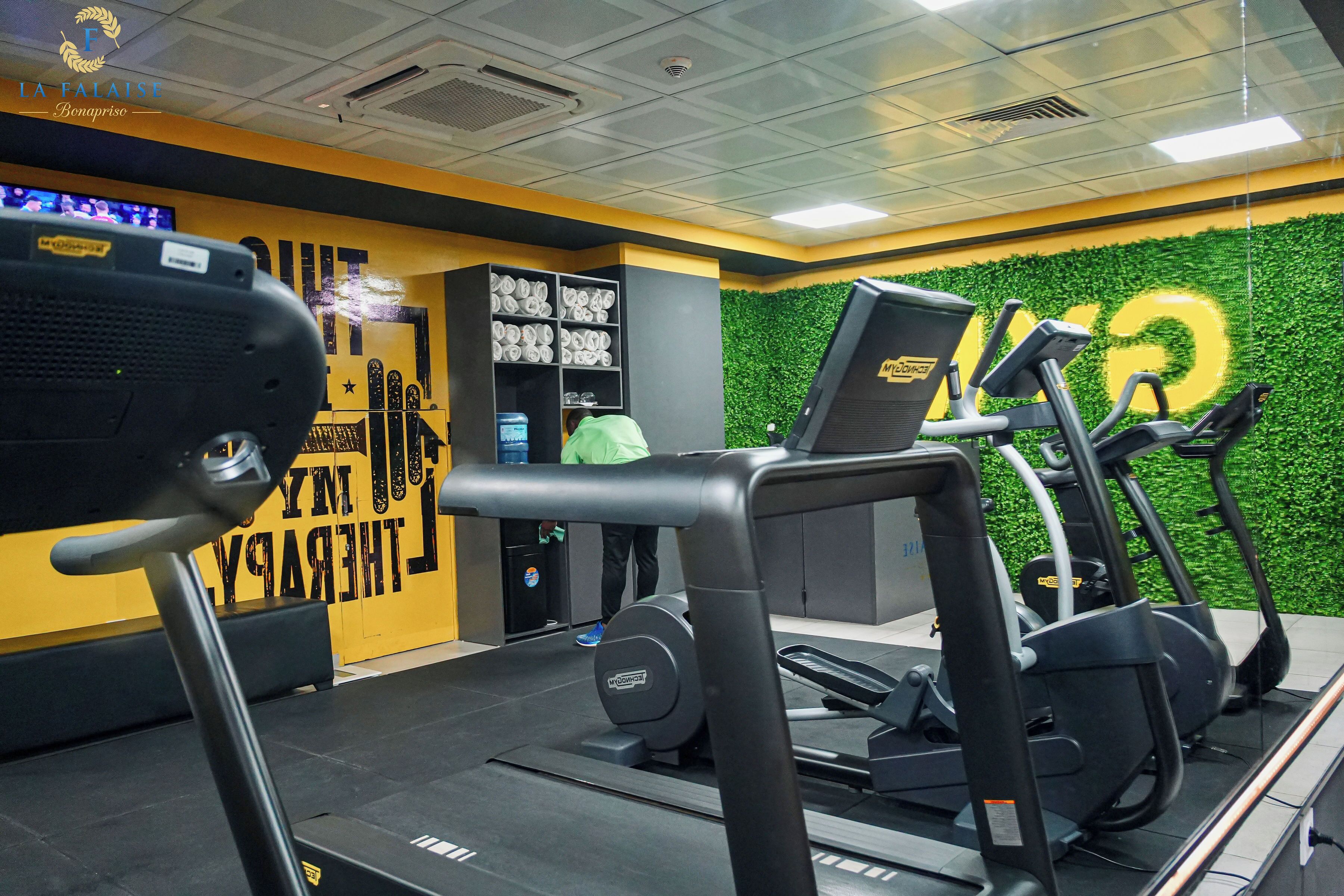 Uma academia com equipamentos de ginástica, um bebedouro e uma parede com um logotipo.