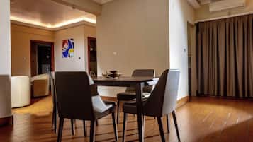 Uma área de refeições com uma mesa de madeira e quatro cadeiras, um quadro na parede e um aparelho de ar condicionado.