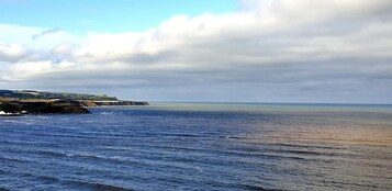 Paisagem costeira com vista para o mar e uma orla rochosa.