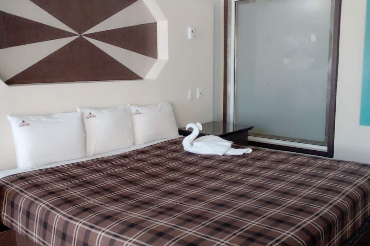 Quarto de hotel com uma cama grande, um espelho e um adorno na parede.