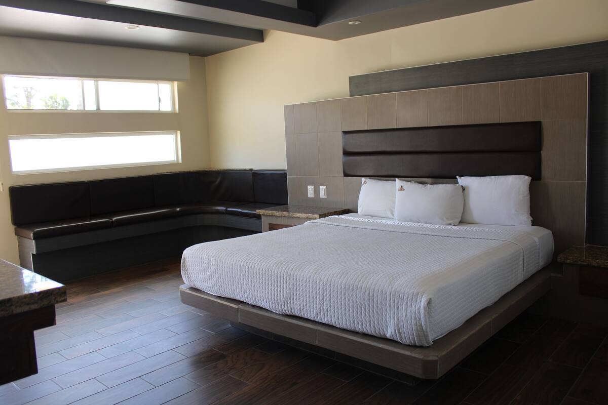 Quarto moderno com cama grande, um banco embutido e janela que proporciona luz natural.