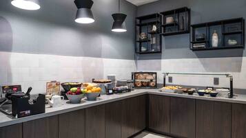 Uma cozinha moderna com bancada para refeições, cafeteira e diversas opções de alimentos.
