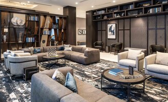 Uma sala de estar moderna com um sofá seccional, poltronas, uma mesa de centro e uma estante cheia de livros e objetos decorativos.