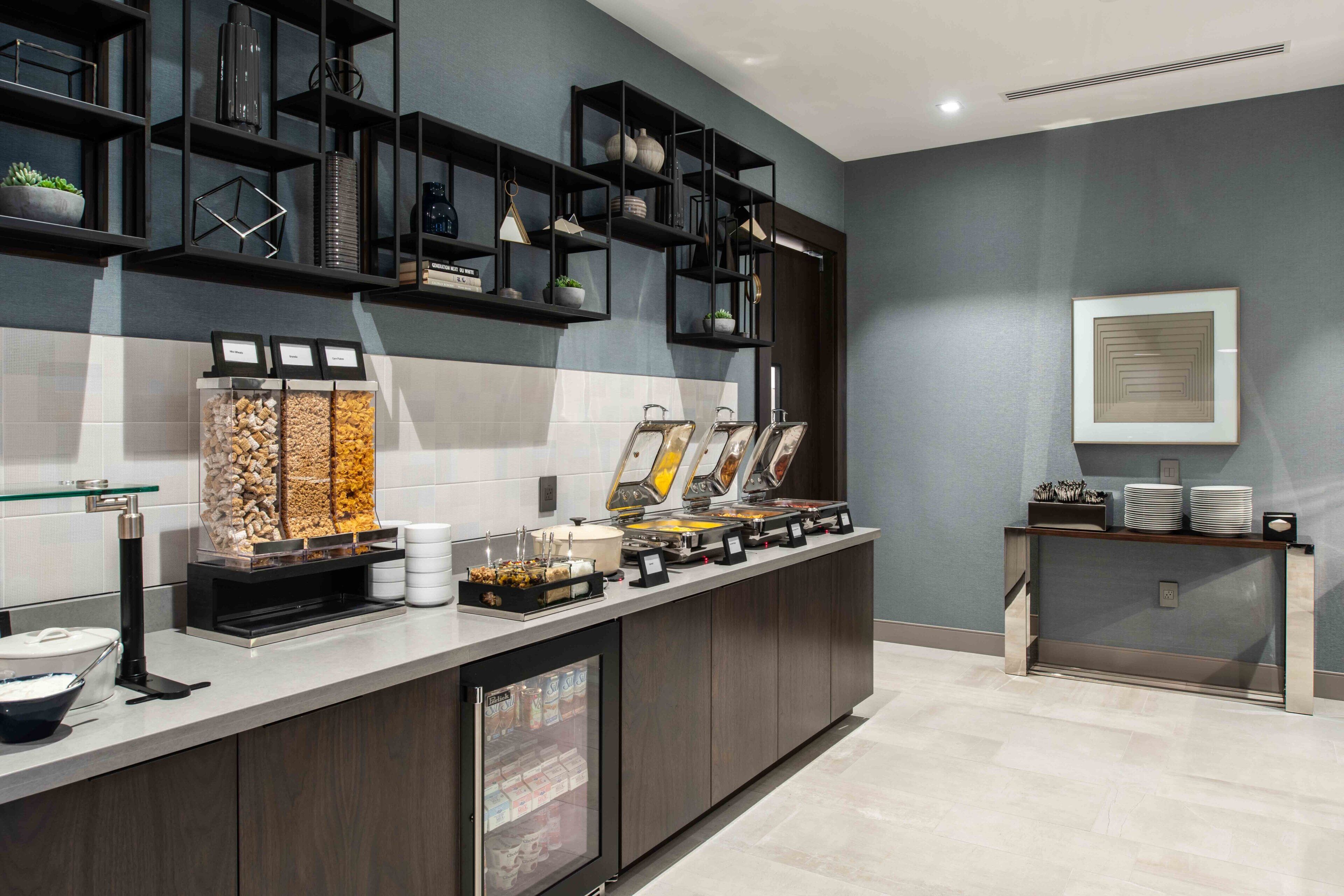 Uma área de refeições moderna com diversas opções de alimentos, uma geladeira e uma máquina de café.