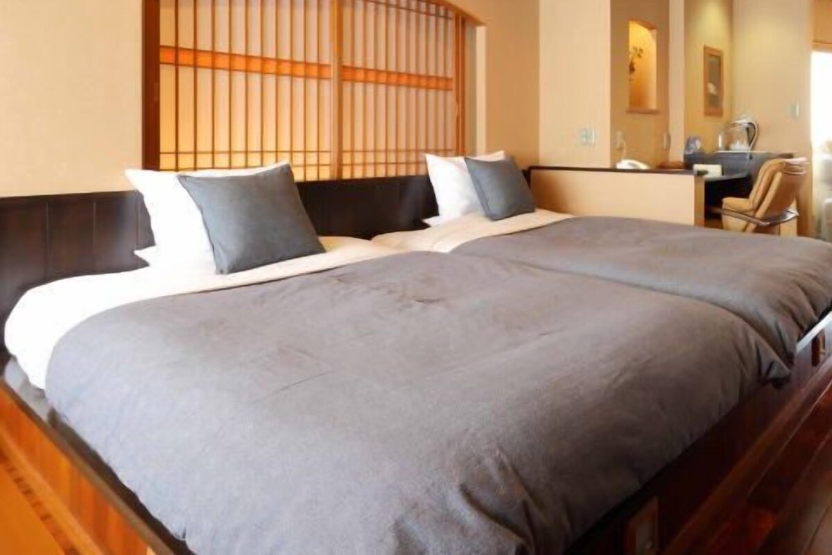 Quarto de hotel com uma cama grande, uma escrivaninha e um espelho.