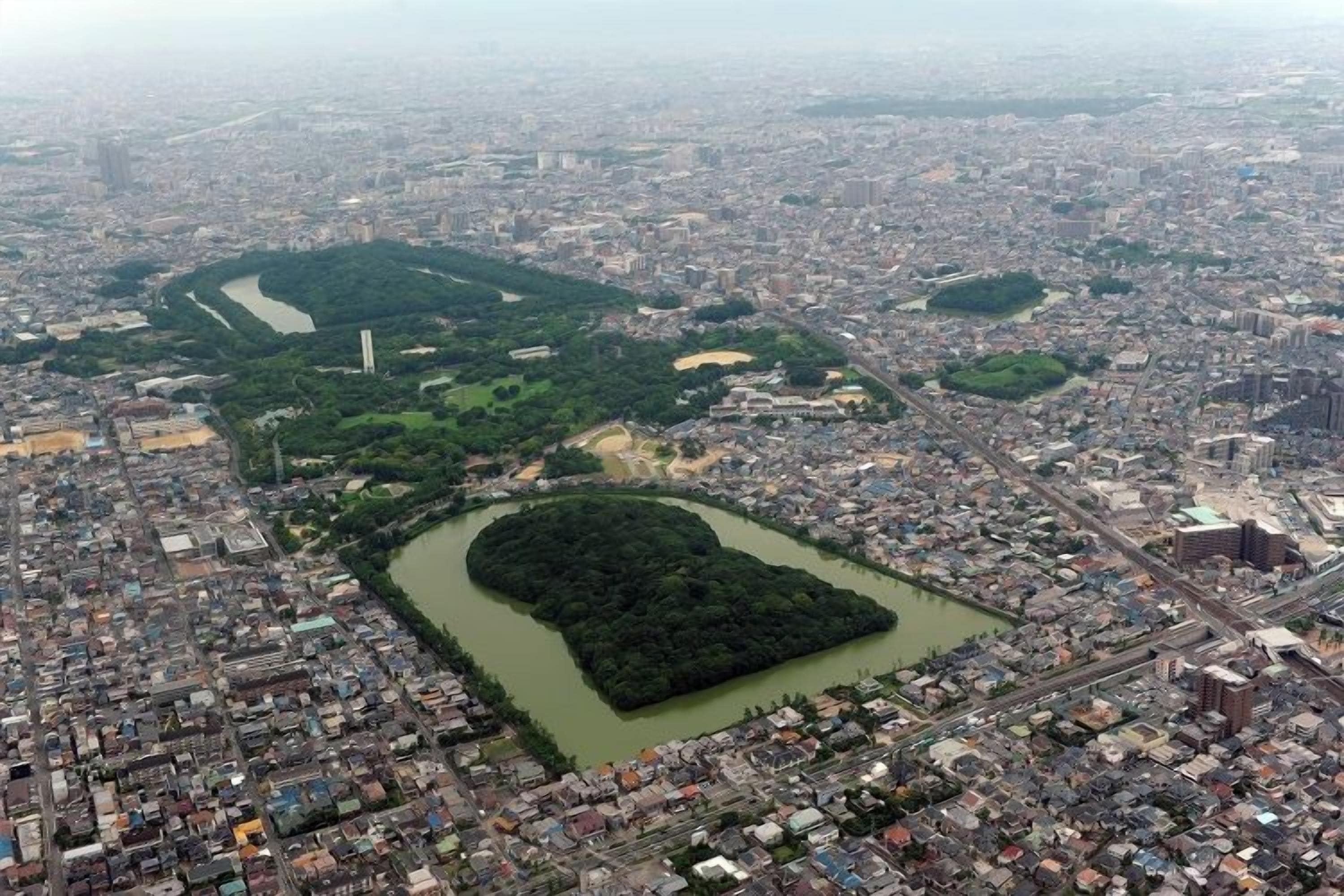 Vista aérea de uma cidade com uma grande área de parque verde, cercada por intenso desenvolvimento urbano.