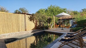 Uma piscina com deck de madeira e cadeiras de descanso.