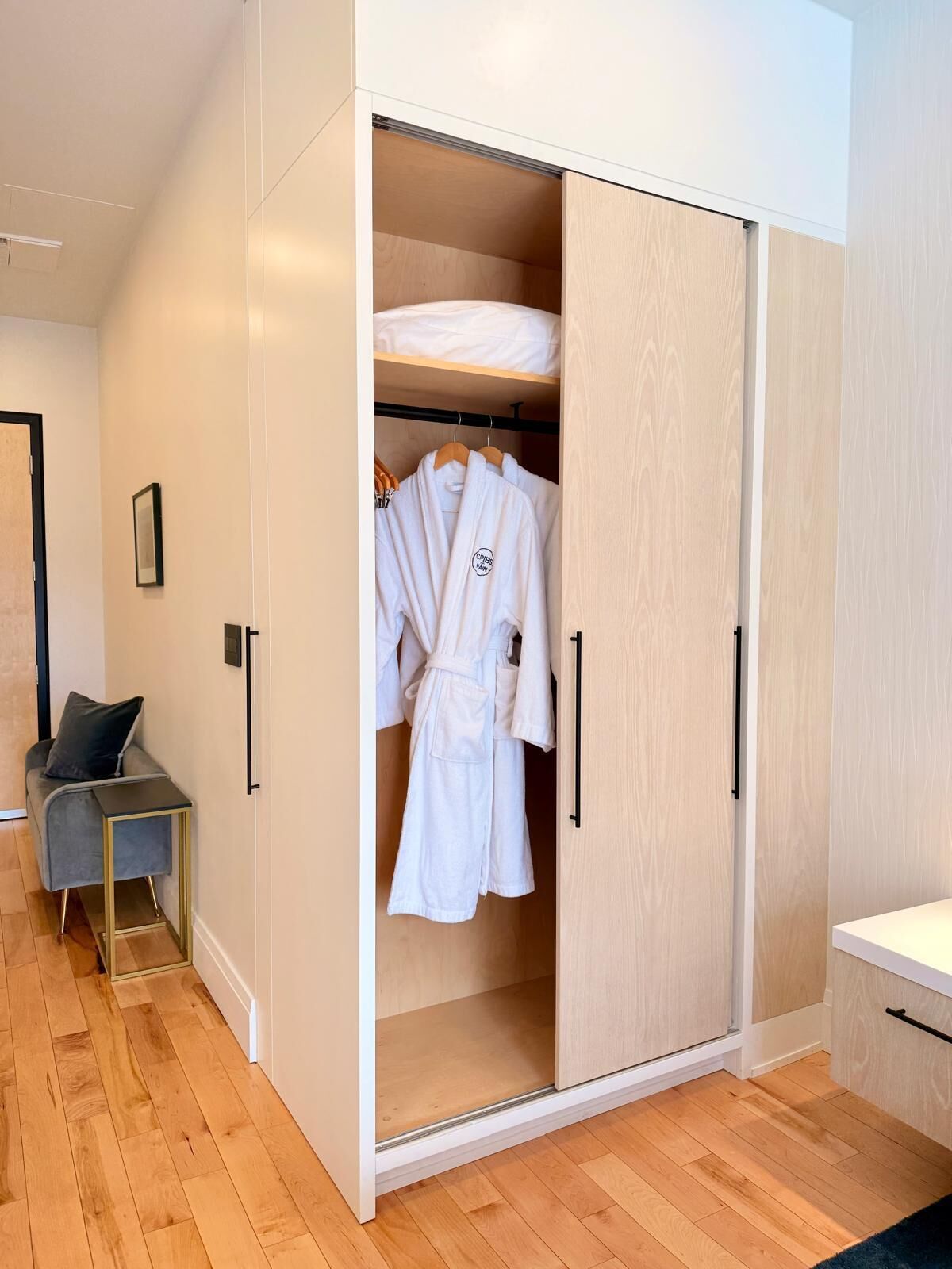 Um closet amplo com piso de madeira, um sofá cinza e uma pequena mesa.