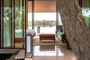 Quarto moderno com uma janela grande, uma cama, um sofá verde e piso de madeira.