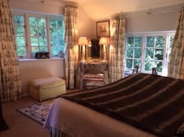Quarto com uma cama grande, mesa de cabeceira, abajur e janela com cortinas.