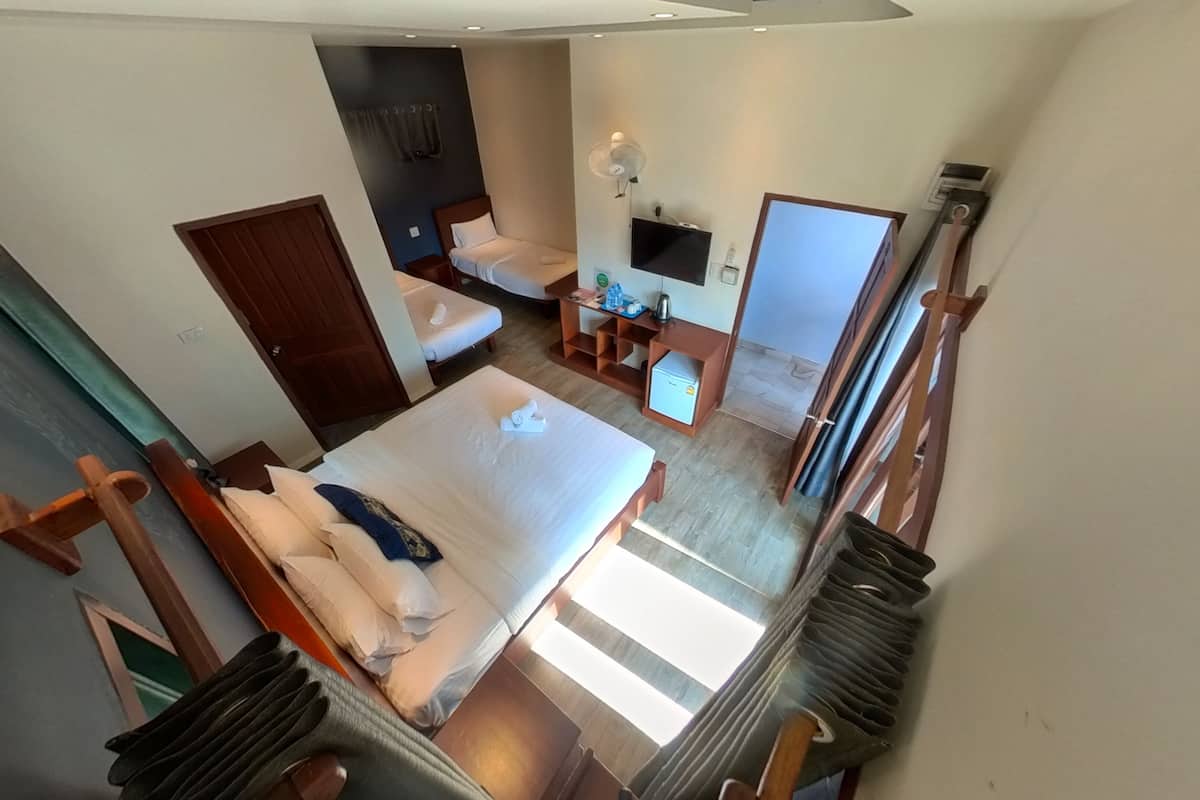 Quarto de hotel com cama, escrivaninha, cadeira, televisão e um pequeno armário.