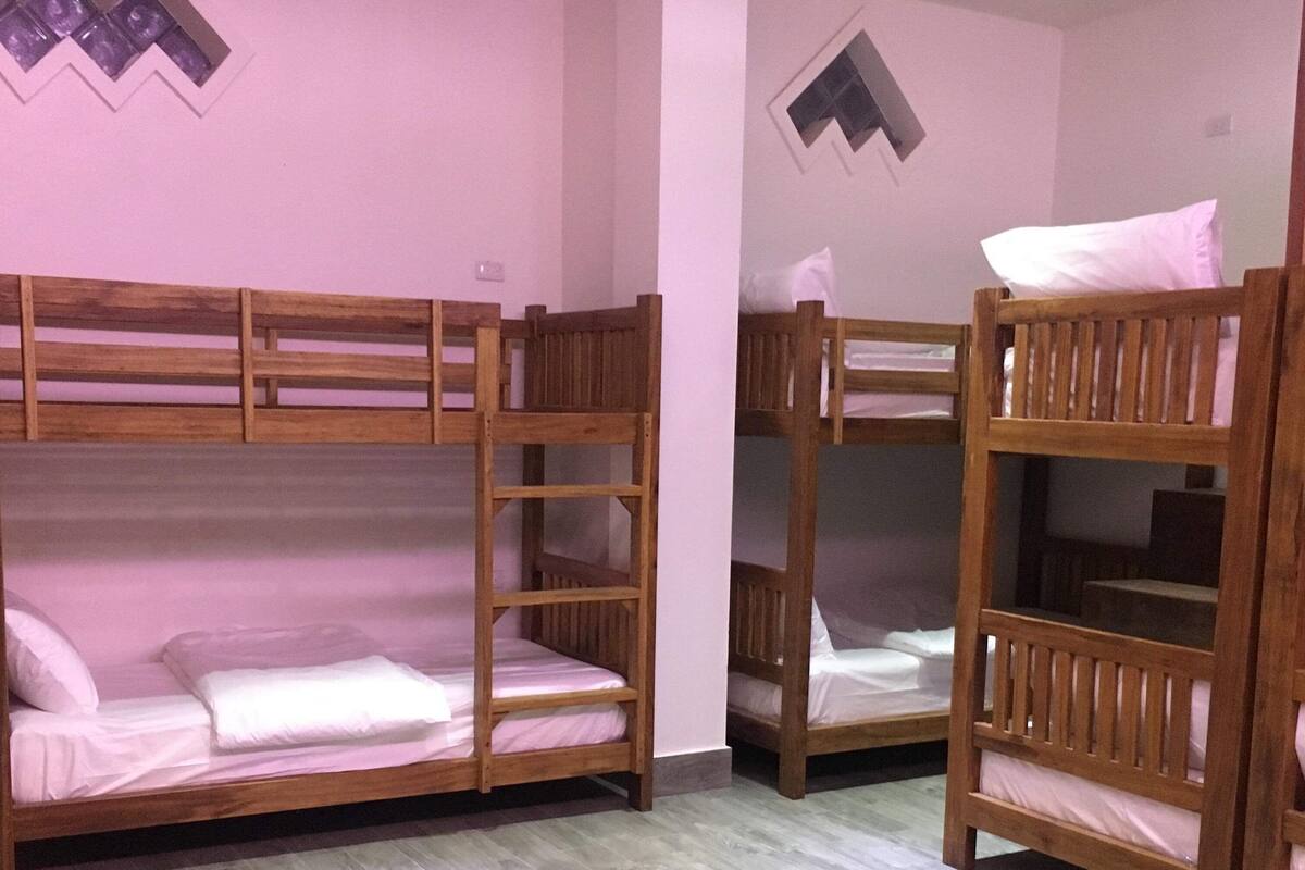 Beliches em quarto com piso ladrilhado e luminária fixada na parede.