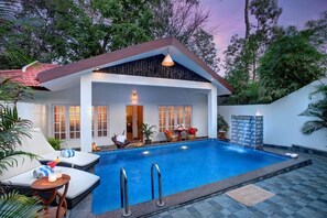 Uma casa moderna com piscina, área de estar externa e uma cascata.